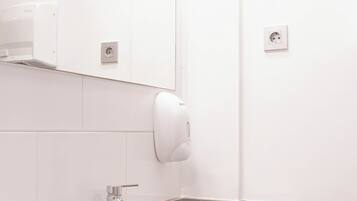 Casa de banho com duas pias, espelho, dispensador de sabonete e porta-toalhas.