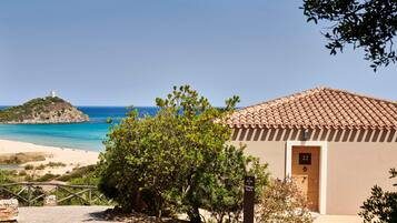 A coastal building with a tiled roof, a door labeled "22", and a view of the beach and sea.