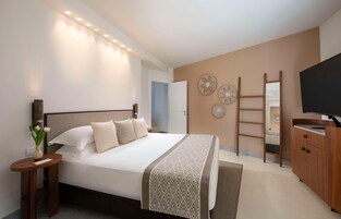 Quarto moderno com uma cama grande, mesas de cabeceira, televisão e guarda-roupa.