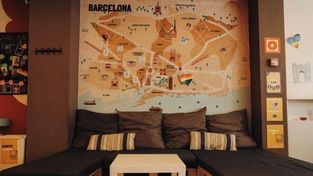 Um quarto aconchegante com um grande mapa de Barcelona na parede, um banco de madeira e uma pequena mesa.