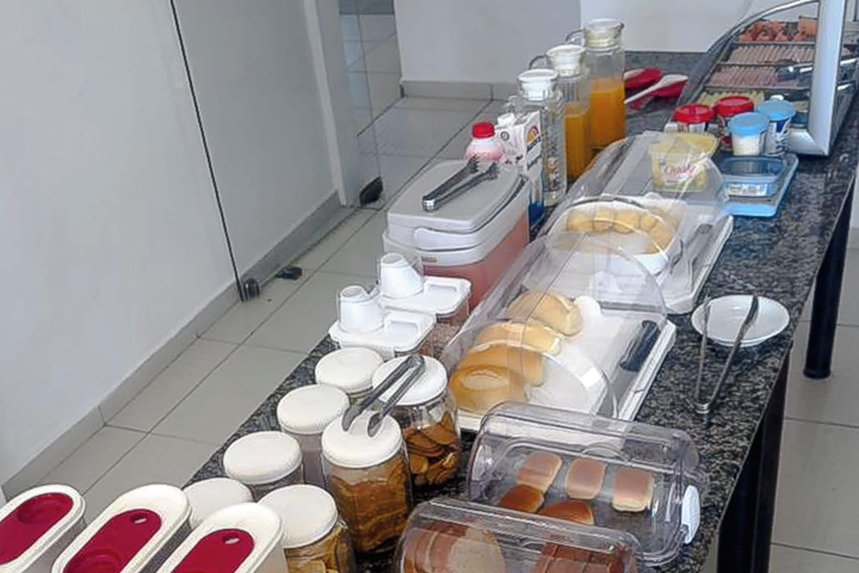 Um buffet de café da manhã com diversos alimentos, acompanhamentos e utensílios.