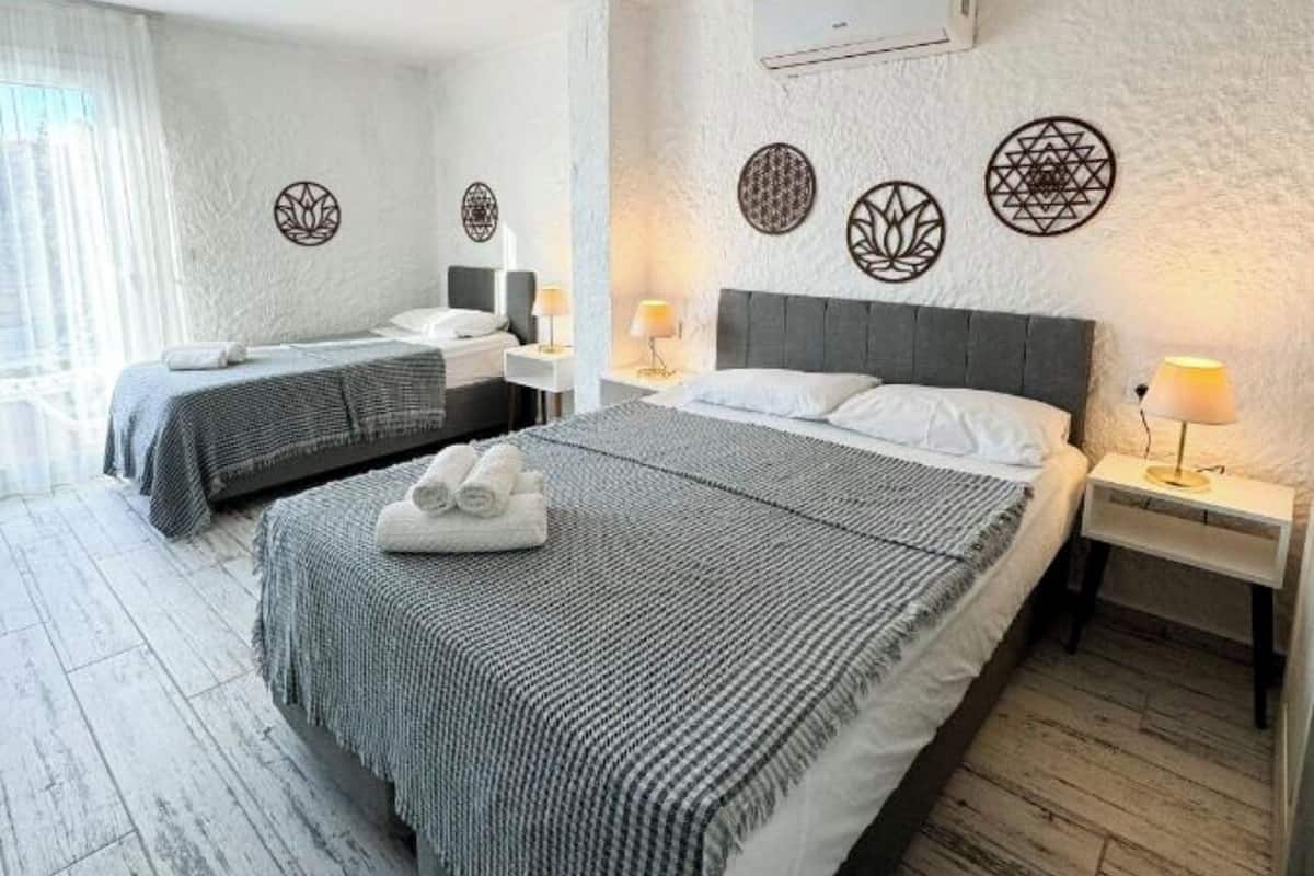 Quarto de hotel com duas camas, uma janela grande e um ventilador de teto.