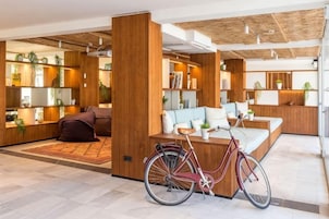 Decoração moderna com um balcão de recepção em madeira, área de estar com sofá e uma bicicleta.