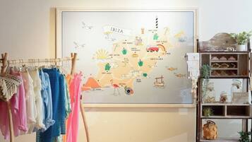 Quarto com mapa de Ibiza, um cabideiro e uma estante com diversos objetos.