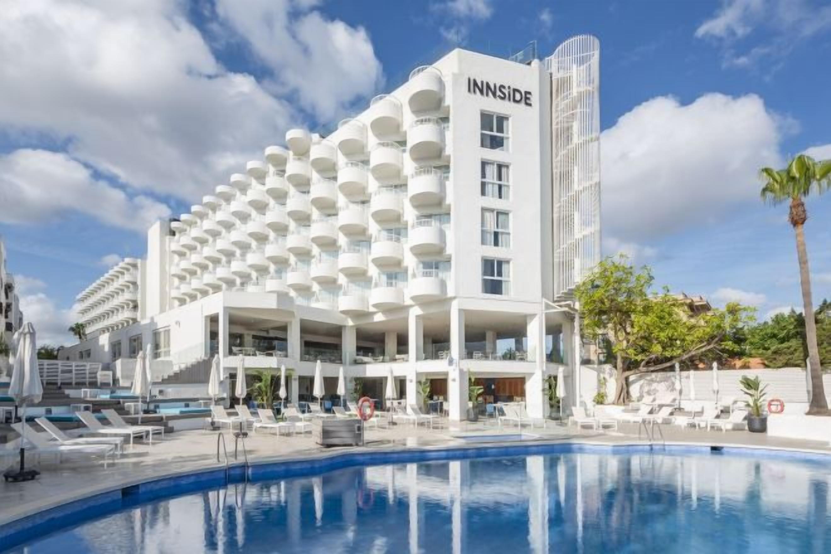 Hotel com piscina, várias varandas e céu limpo.