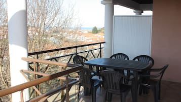 Varanda com mesa e cadeiras, vista para uma área residencial.