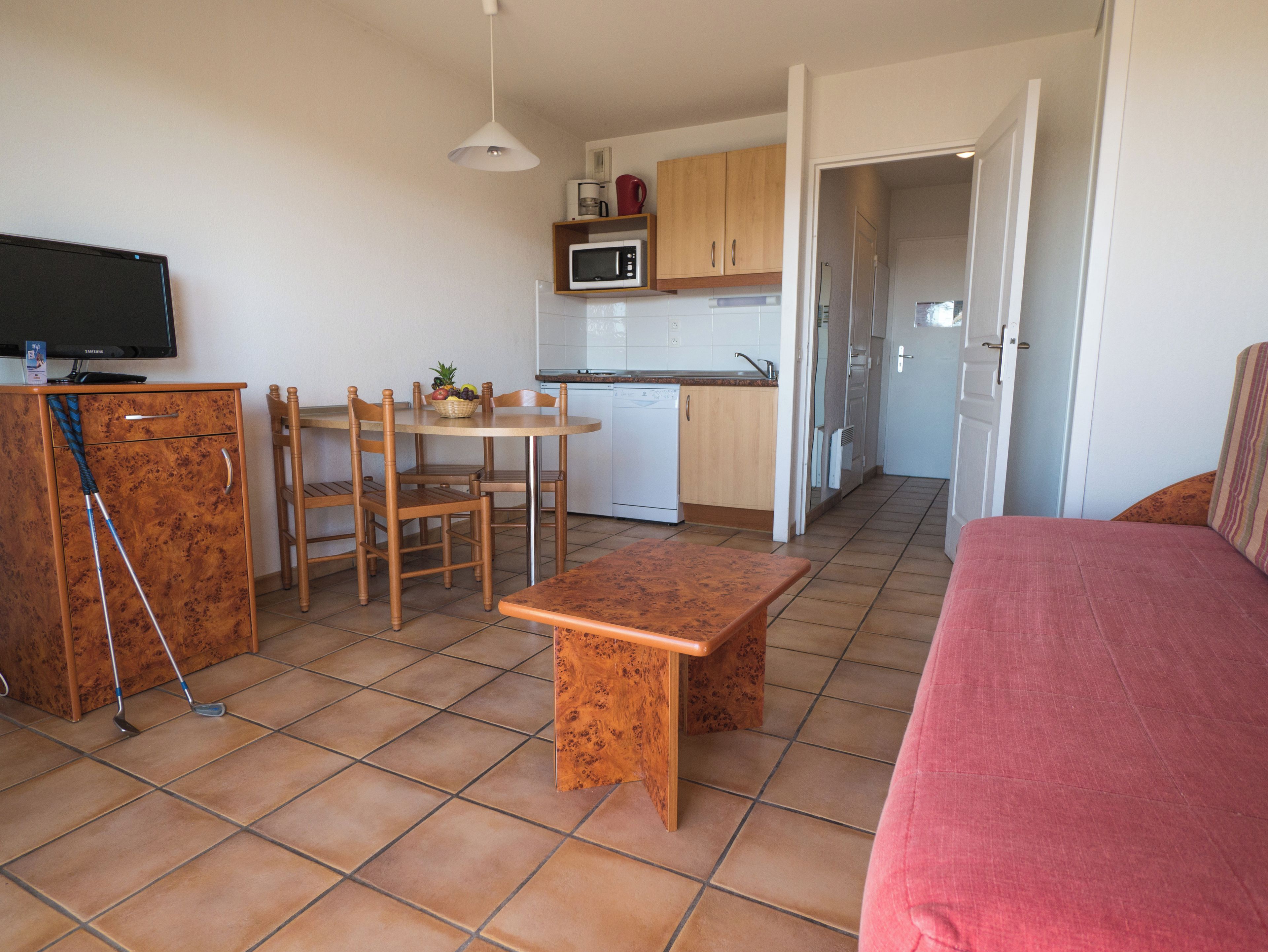 Um espaço de estar compacto com cozinha compacta, área de refeições e espaço para sentar.