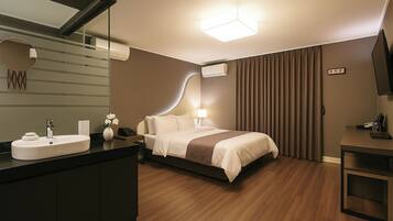 Quarto de hotel com cama, mesa de cabeceira, luminária e um espelho grande.