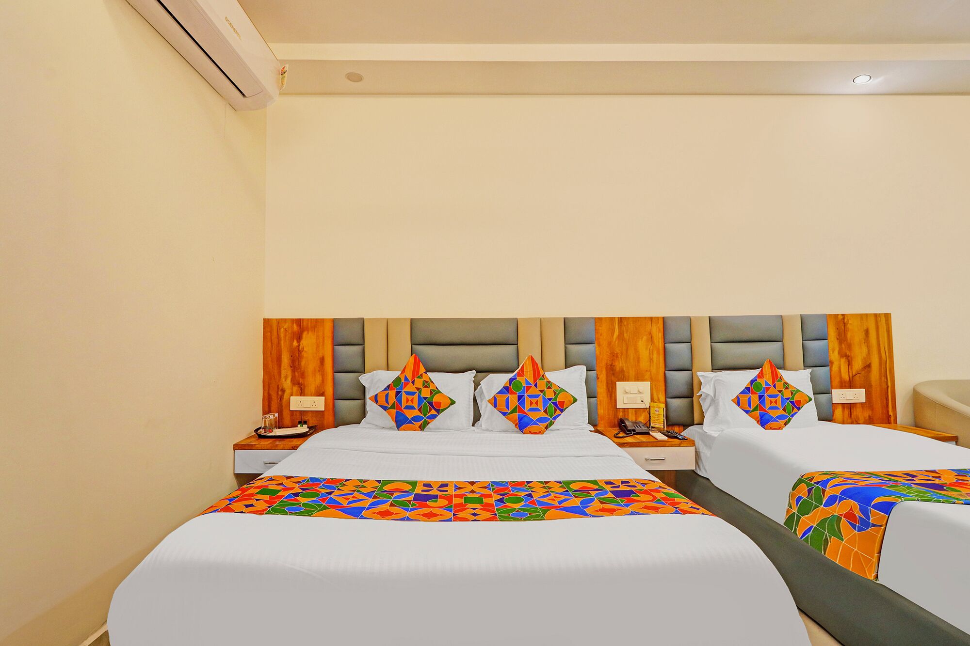 Quarto de hotel com uma cama grande, duas mesas de cabeceira e uma cabeceira com padrão geométrico.