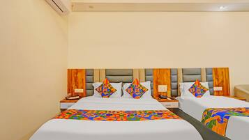 Quarto de hotel com uma cama grande, duas mesas de cabeceira e uma cabeceira com padrão geométrico.