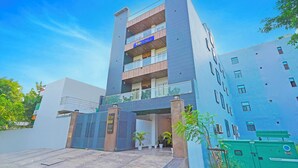 Um hotel moderno com entrada destacada, estrutura de vários andares e placa visível da marca 'Fab Hotels'.