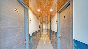 Um corredor moderno com piso lustroso, teto de madeira e portas de vidro.