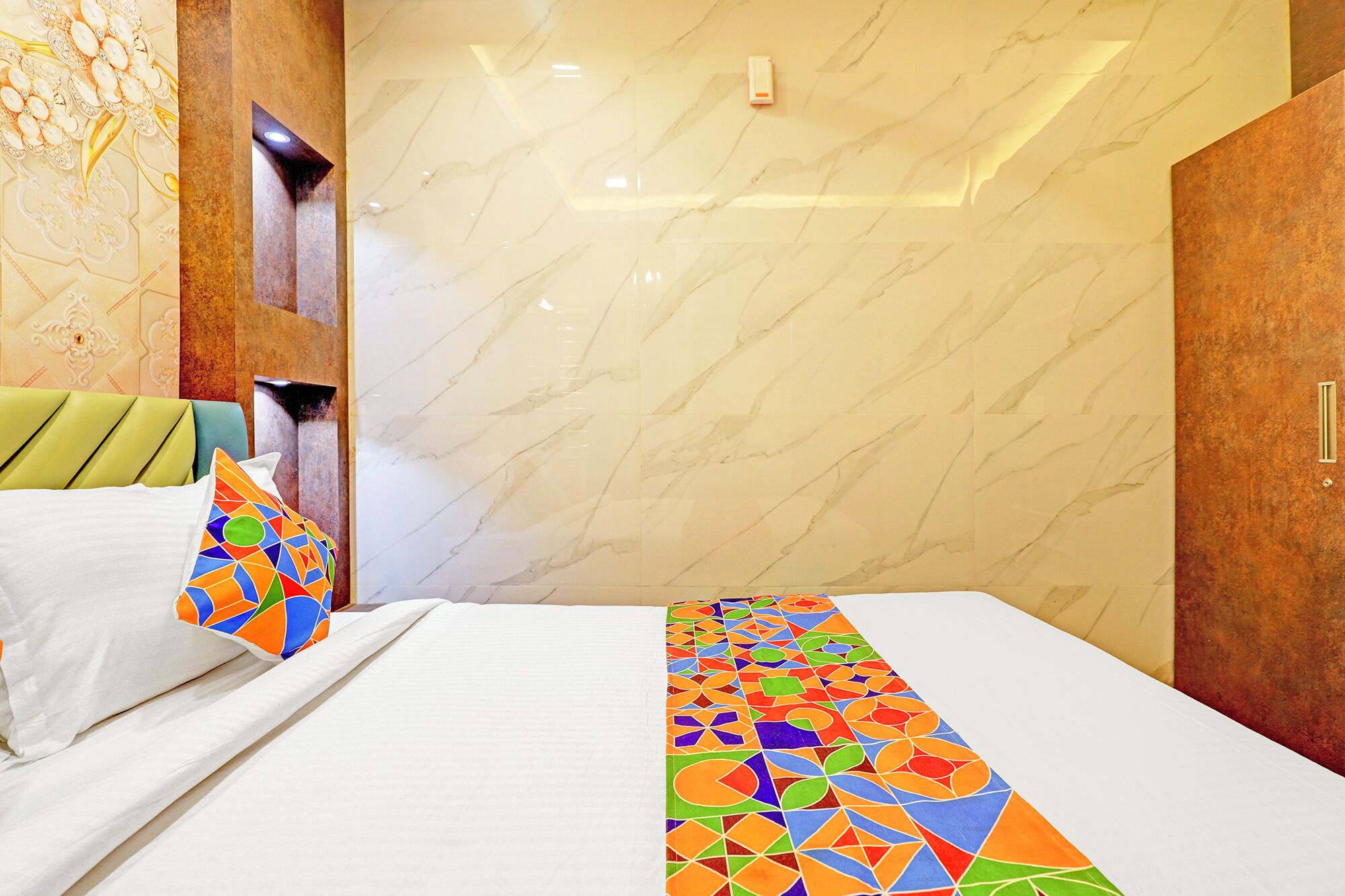 Quarto de hotel com cama, almofadas e decoração na parede.