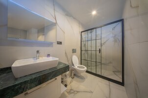 Um banheiro moderno com pia de mármore, box de vidro e um espelho grande.