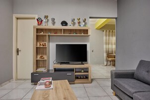 Uma sala de estar moderna com televisão de tela plana, painel de entretenimento de madeira e um sofá cinza.
