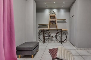 Um banheiro com um banco cinza, uma estante escada de madeira e uma bicicleta.
