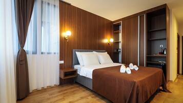 Quarto de hotel moderno com uma cama grande, painéis de madeira, um guarda-roupa e uma mesa de cabeceira.