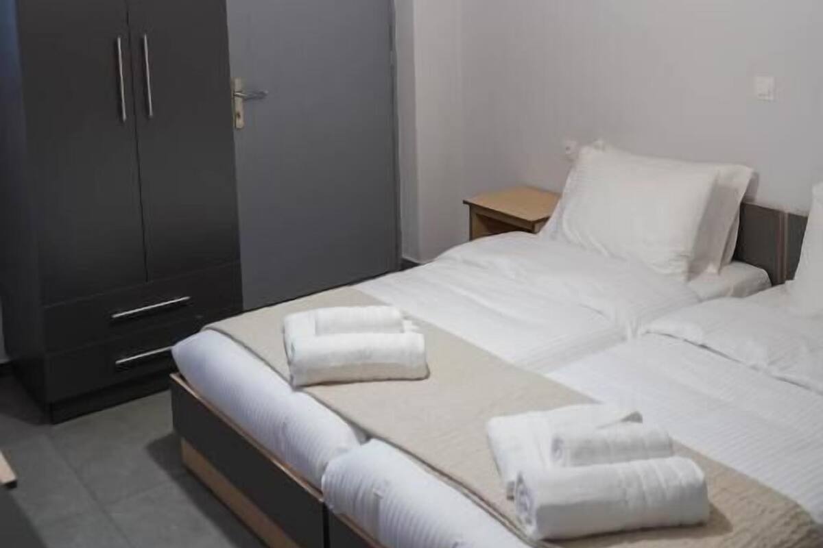 Quarto de hotel moderno com cama, guarda-roupa e mesa de cabeceira.
