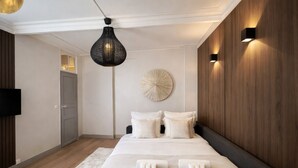 Um quarto moderno com uma cama grande, uma decoração redonda na parede e um luminário pendente único.