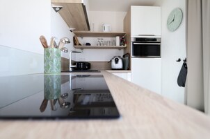 Cozinha moderna com bancada preta, armários de madeira e forno embutido.