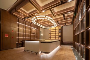 Um lobby moderno com uma receção central, painéis de madeira e um design de teto único.