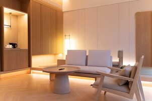 Uma sala de estar moderna com uma mesa de centro redonda, um sofá e uma poltrona.