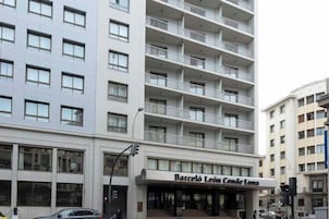 Um edifício moderno com vários andares, varandas e uma loja com o nome "Barcelo León Conde Luna".