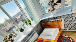 Um quarto aconchegante com cama, janela e vista para prédios.
