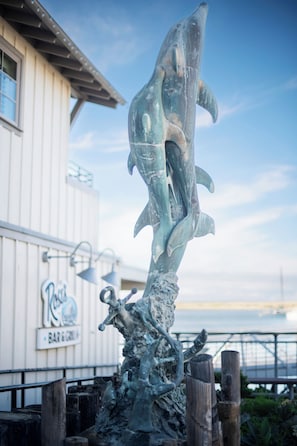 Uma escultura de golfinho em frente a um edifício com uma placa que diz 'Bar & Grill'.