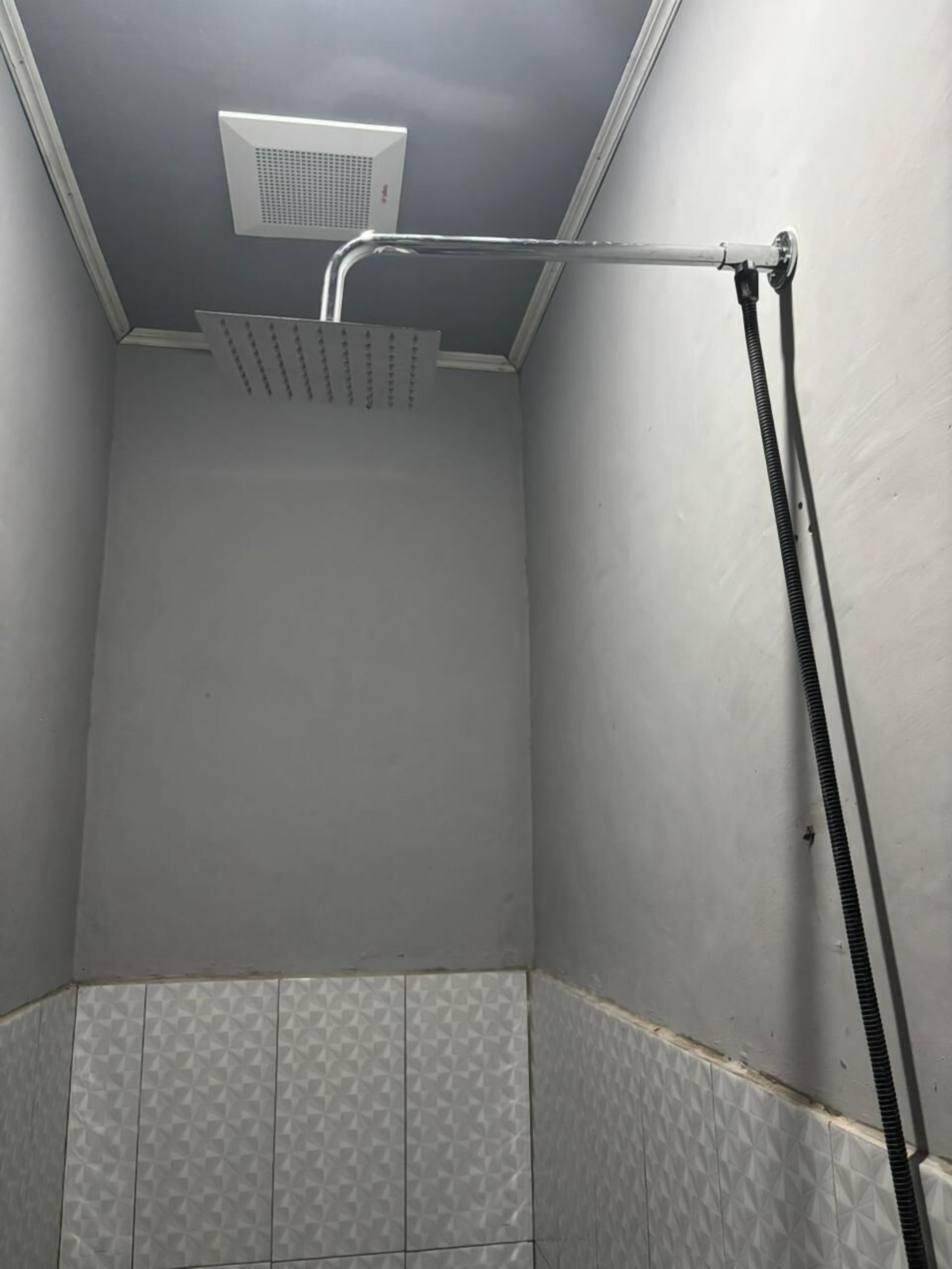 Chuveiro com chuveiro de teto e mangueira flexível.