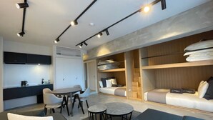 Quarto de hotel moderno com área de refeições, sofá e cama com prateleiras.