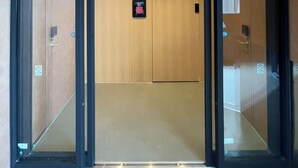Elevador moderno com portas de vidro e visor digital.