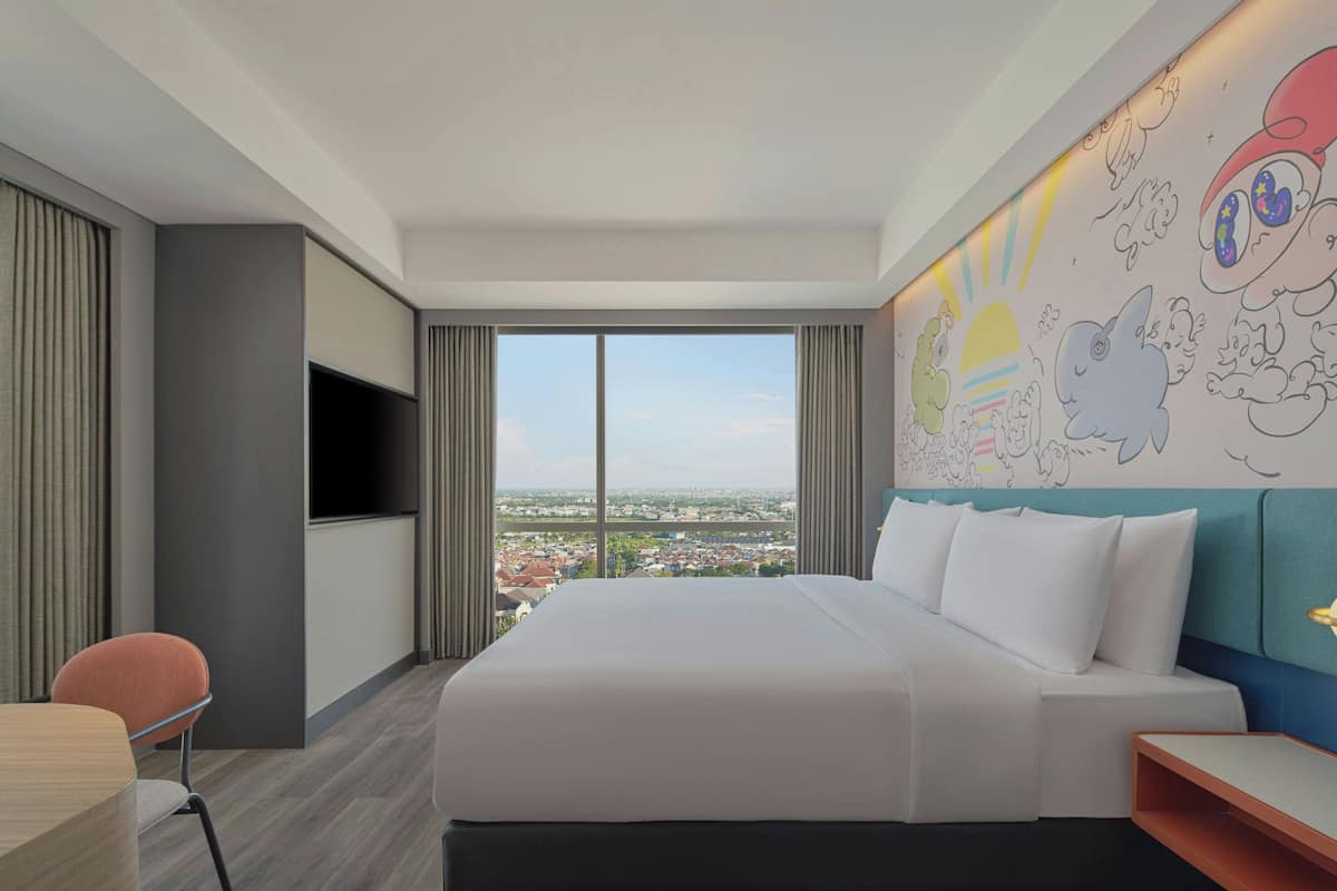 Quarto de hotel moderno com uma cama grande, televisão e vista para a cidade.
