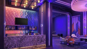 Uma área de bar moderna com bancada de mármore, televisão de tela plana e diversos tipos de bebidas.