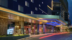 Um hotel moderno com fachada de vidro, sinalização iluminada e área de entrada bem iluminada.