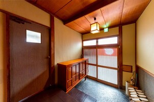 Um interior japonês tradicional com porta de madeira, divisória shoji deslizante, chão de tatame e um banco de madeira baixo.