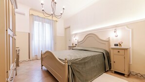 Quarto com cama, mesa de cabeceira, cómoda e um candelabro.