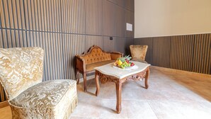 Um quarto com um sofá estampado, uma cadeira de madeira, uma mesa com frutas e uma parede listrada.