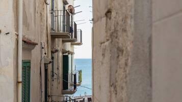 Uma rua estreita ladeada por edifícios, que leva a um corpo de água.
