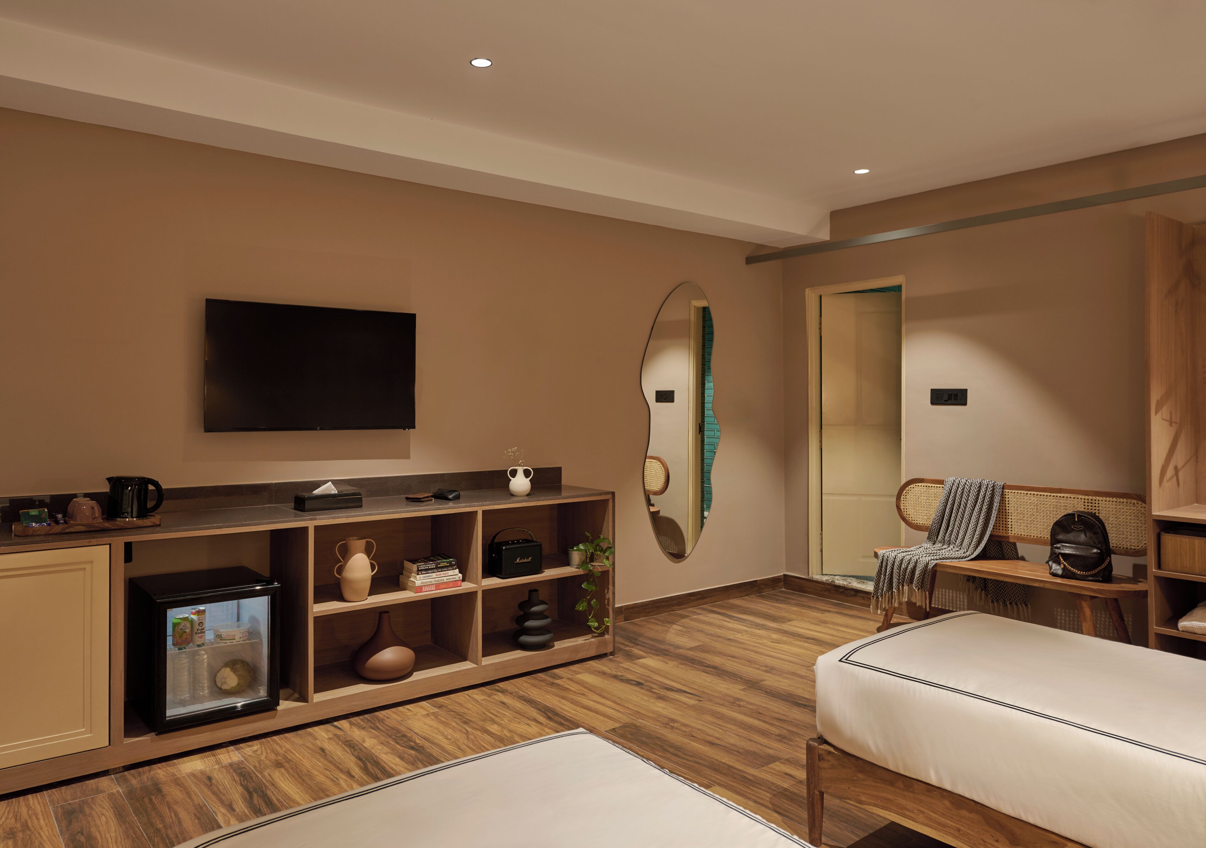 Quarto moderno com televisão de tela plana, um espelho, sofá, mesa de centro e um pequeno armário.