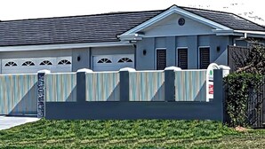 Uma casa de dois andares com garagem, painéis solares e acesso por portão.