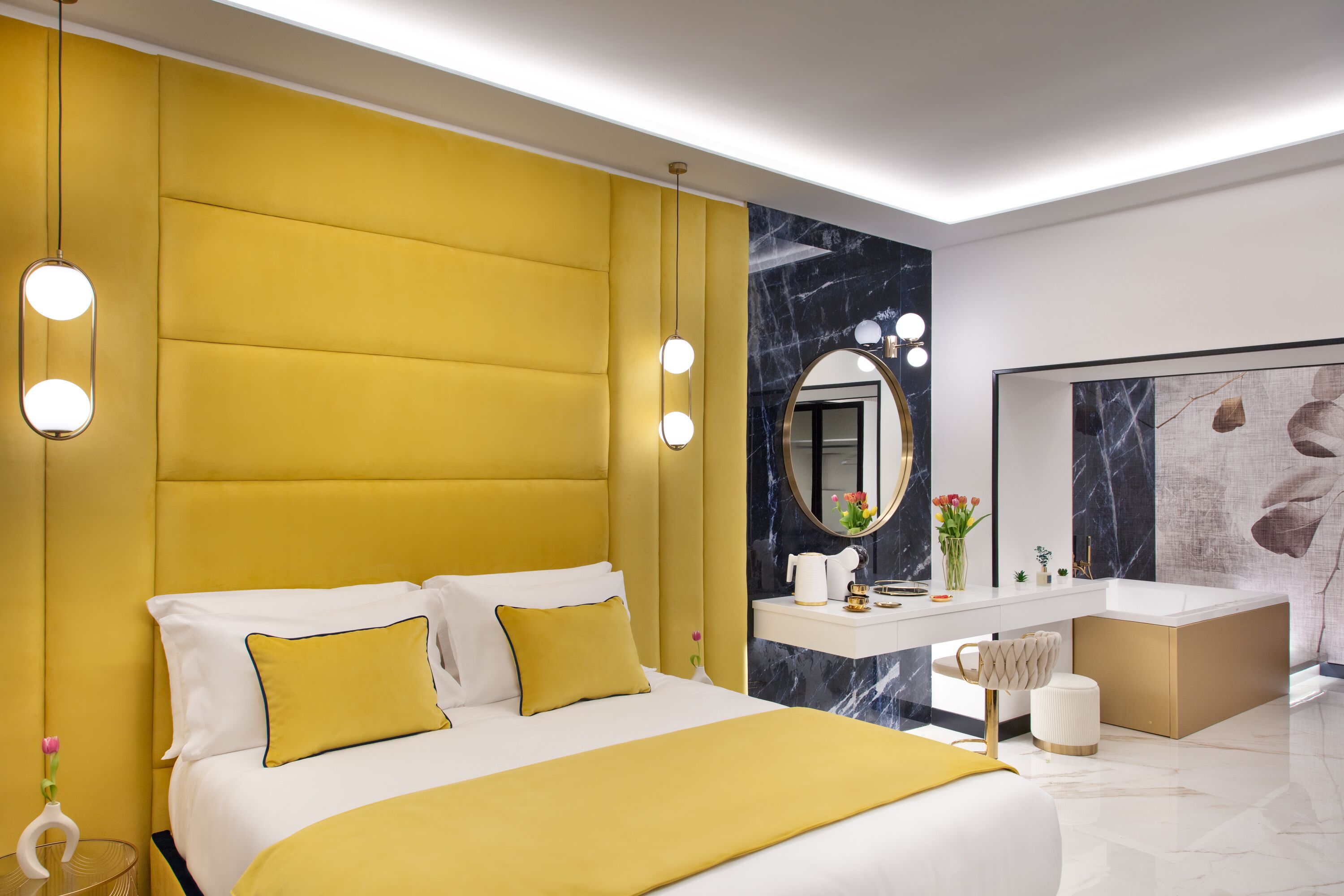 Quarto de hotel moderno com uma cama grande, uma toucador com espelho e um banheiro com banheira e vaso sanitário.
