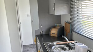Uma cozinha compacta com pia, escorredor de louça e armários de armazenamento.