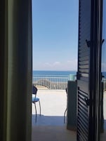 Uma varanda com vista para o mar, uma cadeira e uma mesa.