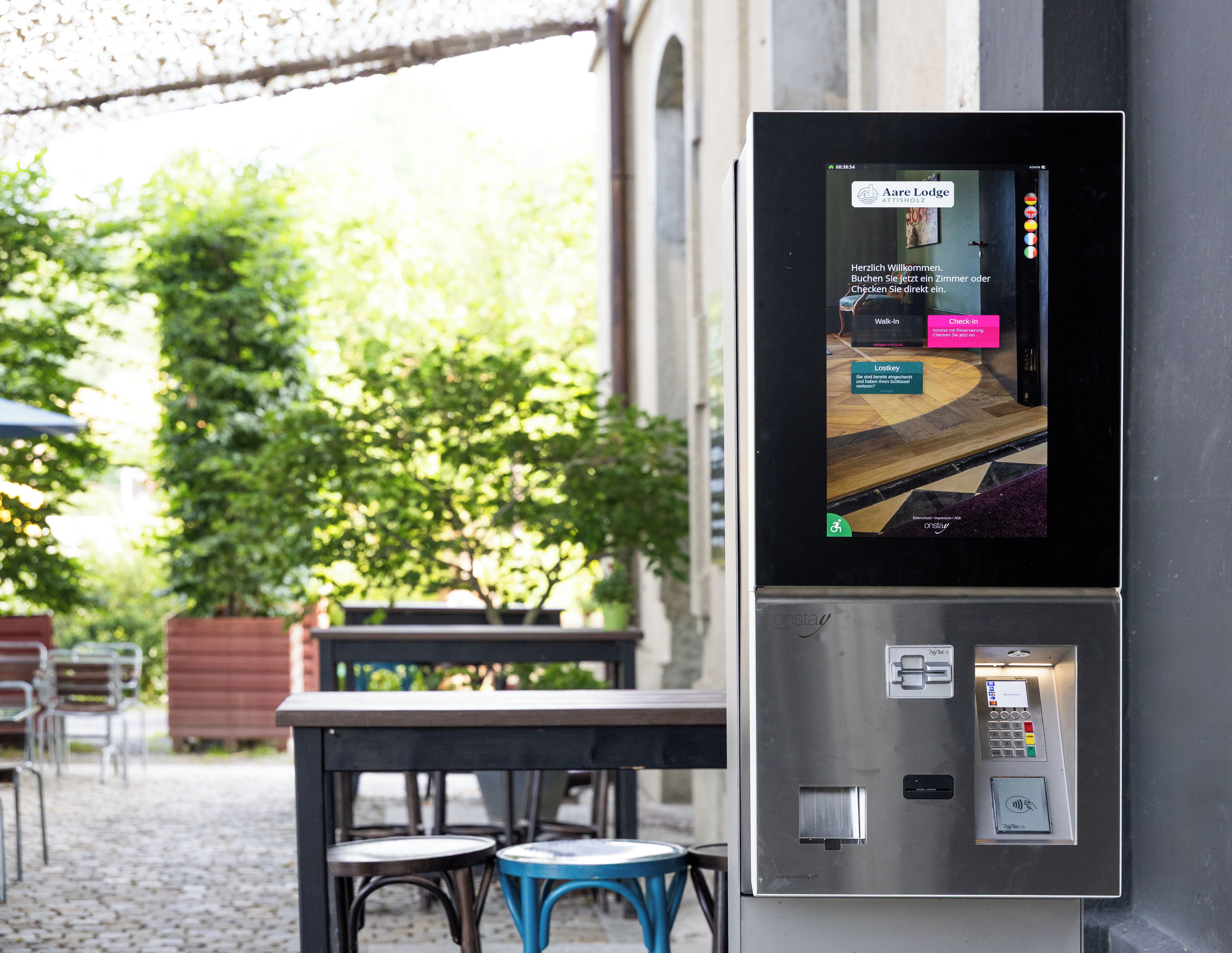 Um quiosque digital com tela exibindo uma mensagem de boas-vindas e opções para reservar um quarto ou realizar o check-in.