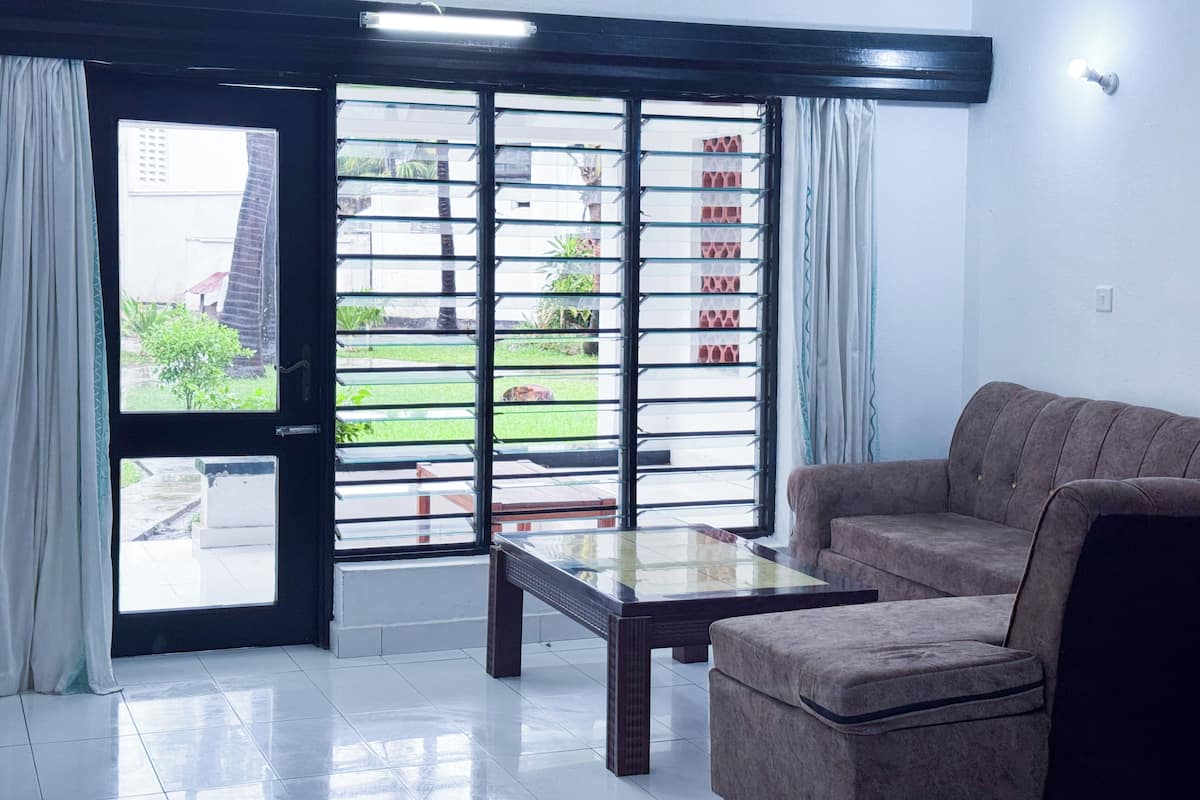 Uma sala de estar com porta de vidro deslizante, um sofá e uma mesa de centro.