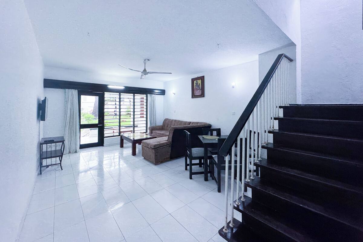 Uma sala de estar ampla com sofá, mesa de centro e escada.