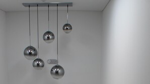 Escadaria com corrimãos de metal e luminárias esféricas penduradas.