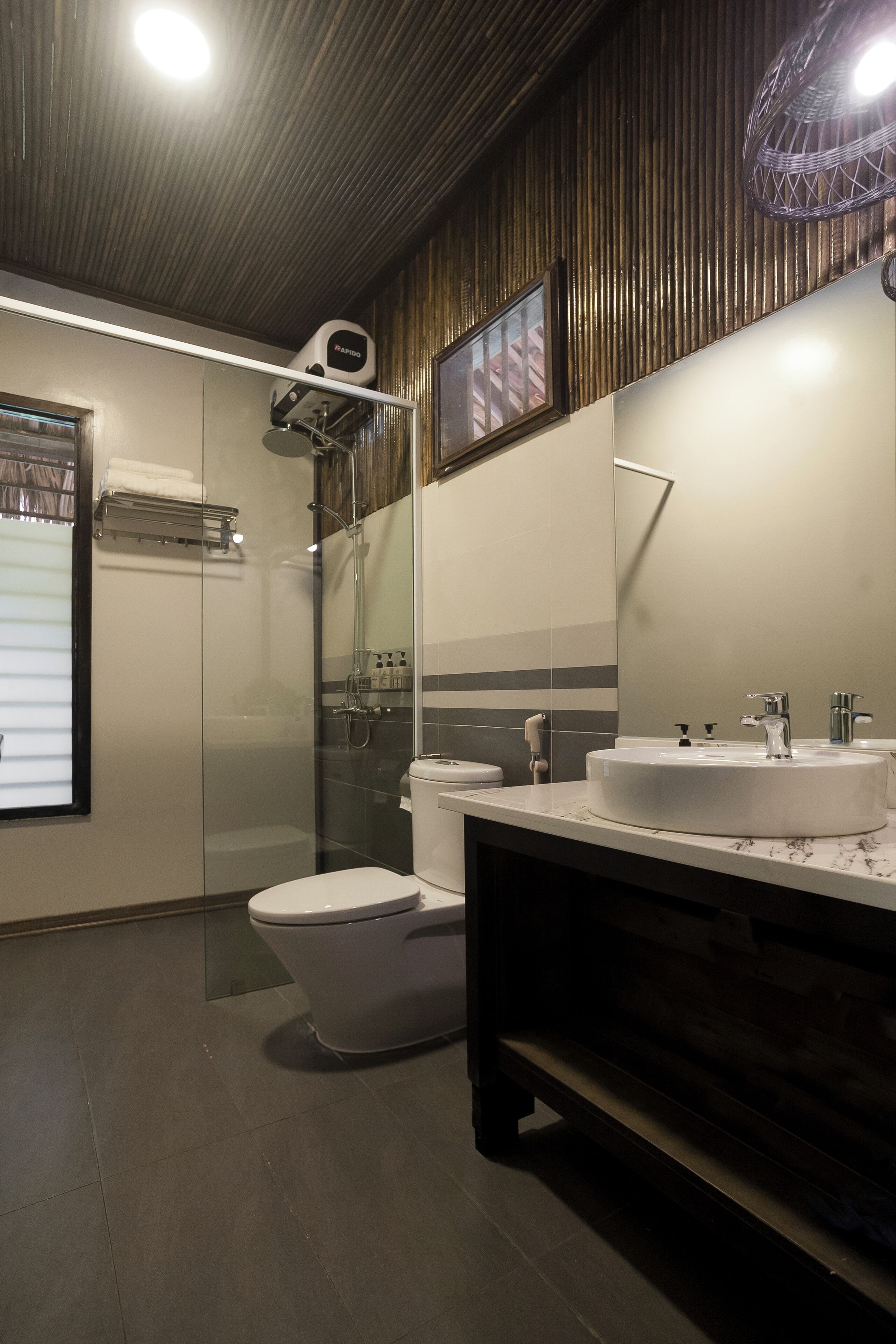 Uma casa de banho moderna com chuveiro em cabine de vidro, sanita e lavatório com espelho.