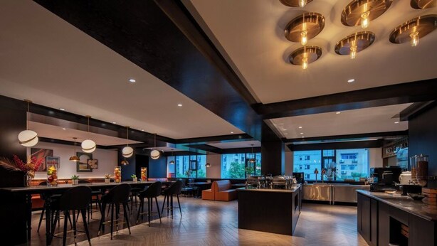 Uma cozinha moderna com uma ilha central, área de bar com banquetas e janelas amplas com vista para a cidade.